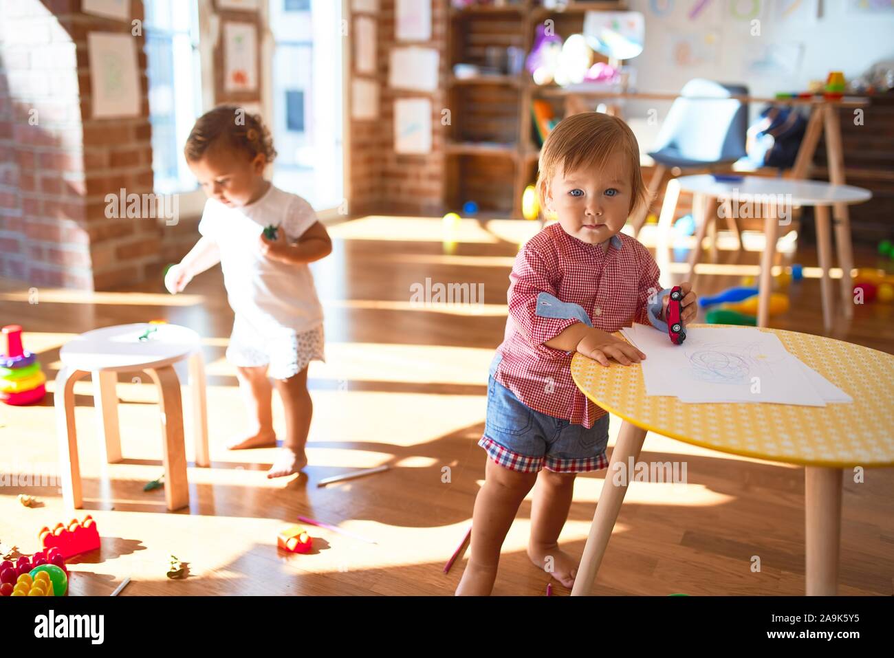Adorable toddlers playing around lots of toys at kindergarten Stock ...