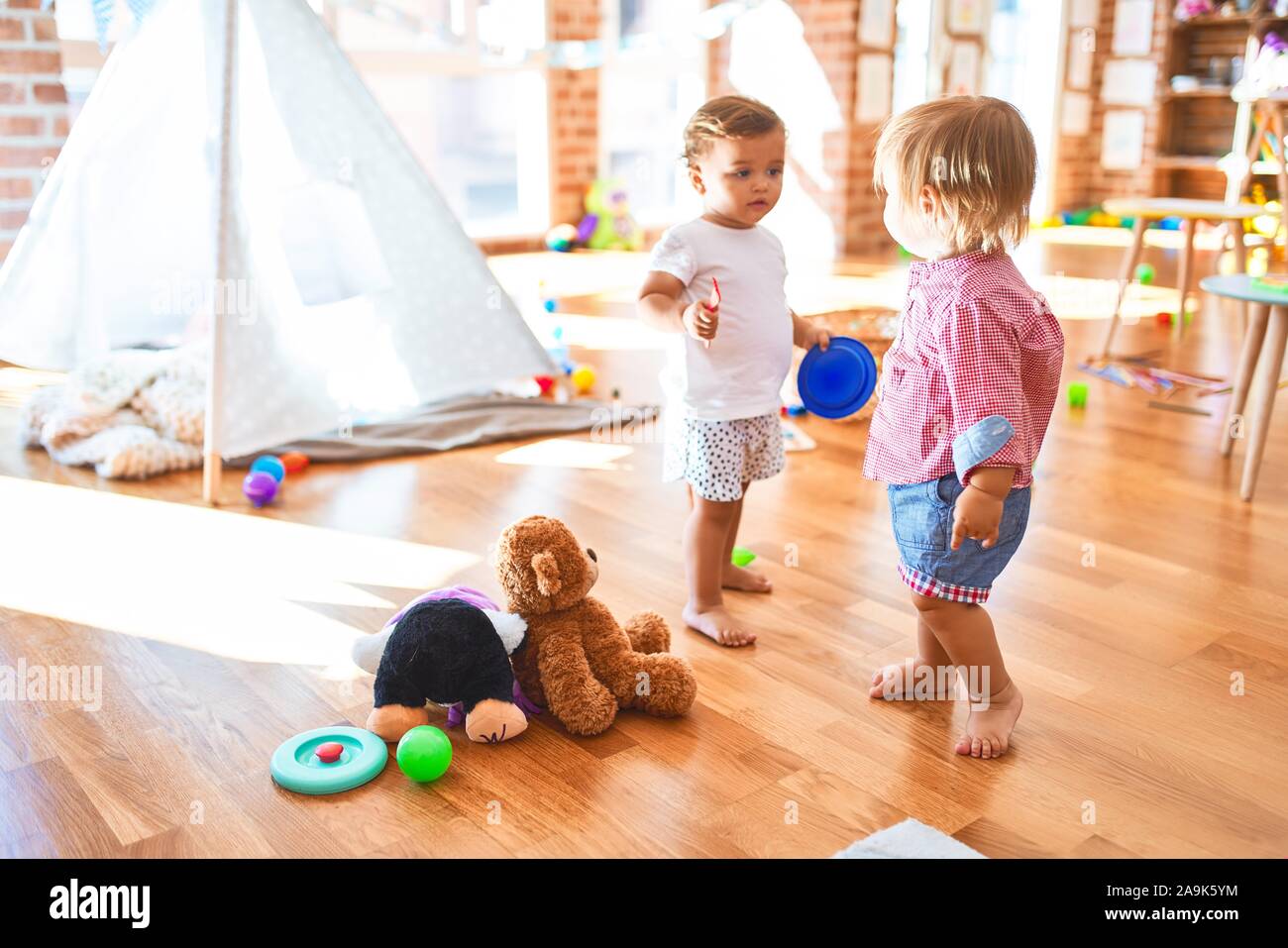 Adorable toddlers playing around lots of toys at kindergarten Stock ...