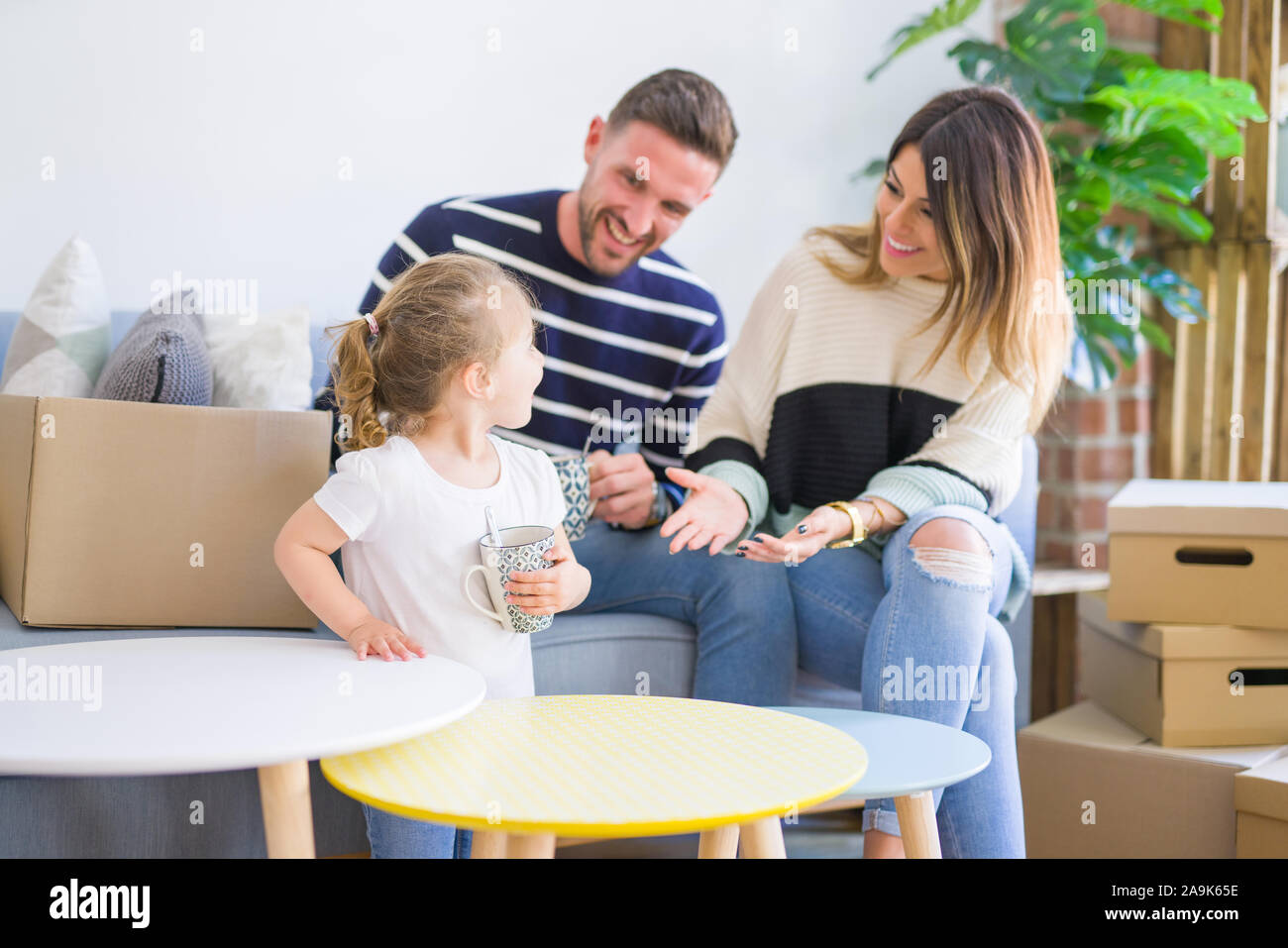 Beautiful family, parents sitting on the sofa drinking coffee looking ...