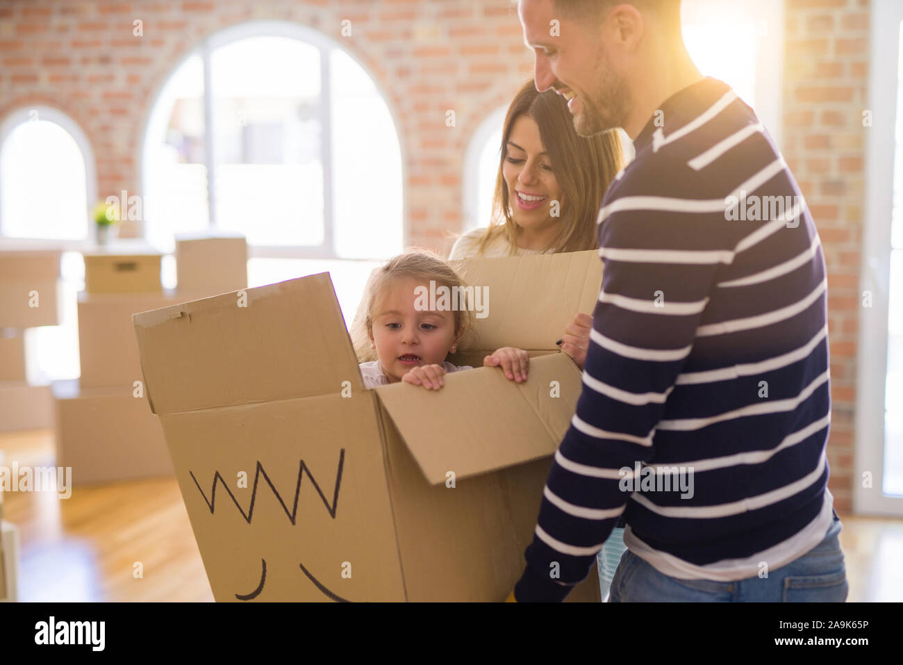 Beautiful famiily, kid playing with his parents riding fanny cardboard ...