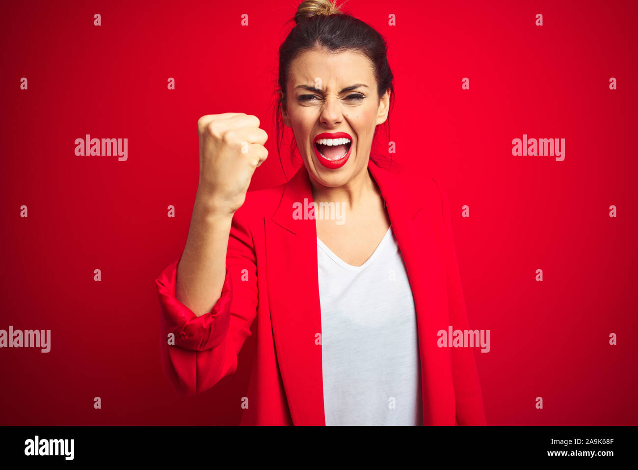 Young beautiful business woman standing over red isolated background ...