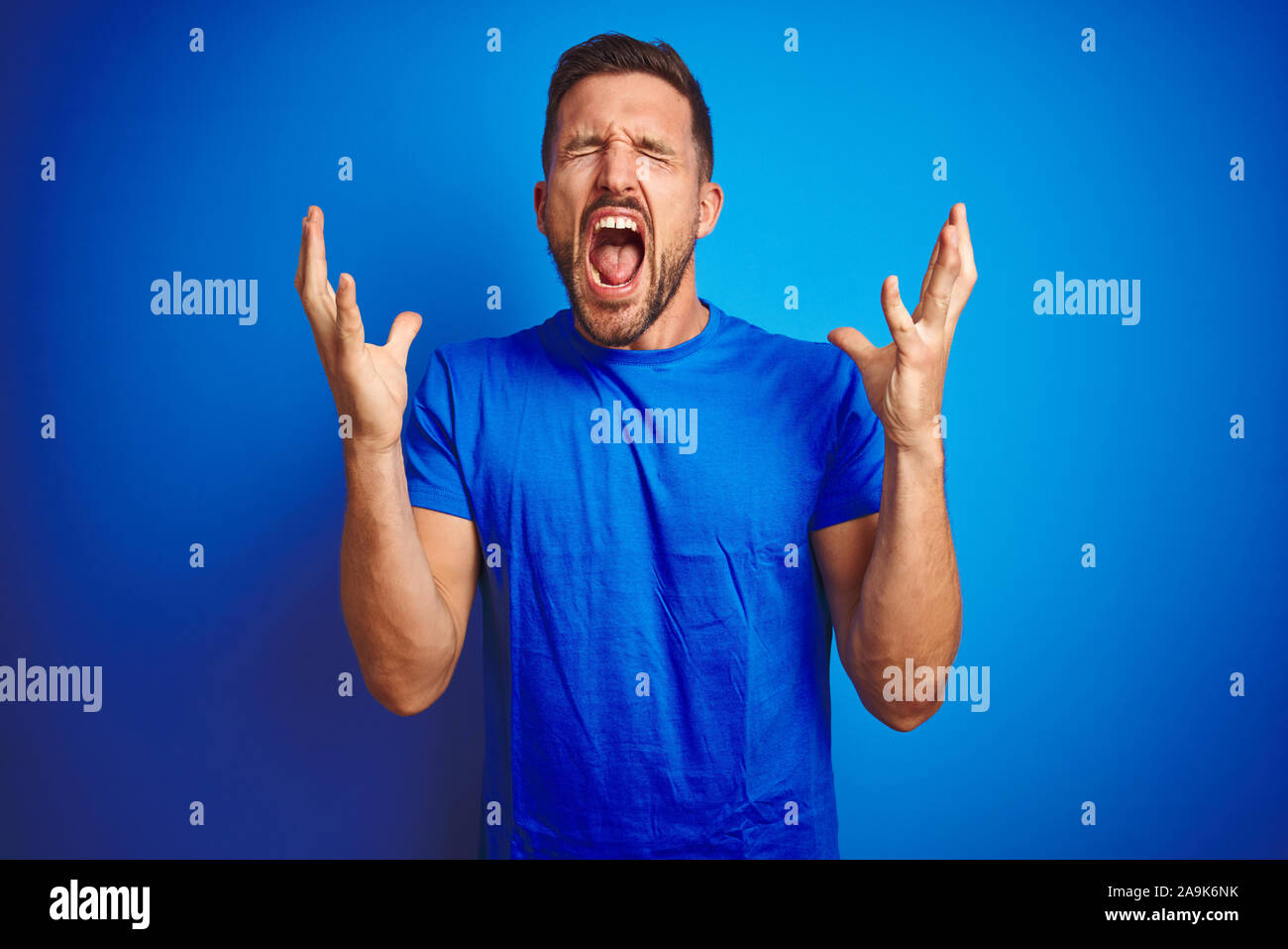 Young handsome man wearing casual t-shirt over blue isolated background ...