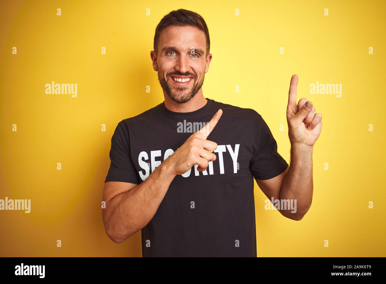 Young safeguard man wearing security uniform over yellow isolated ...