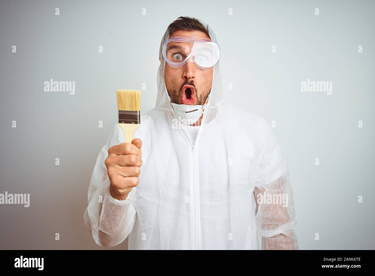 Painter man wearing professional worker equipment holding brush over ...