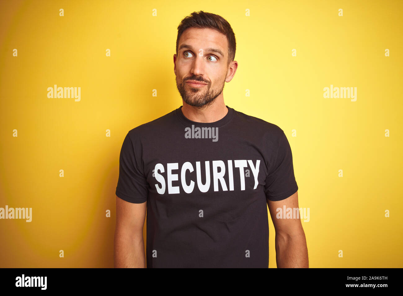 Young safeguard man wearing security uniform over yellow isolated ...
