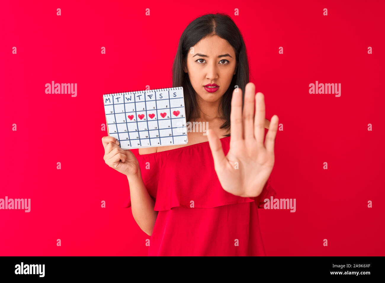 Young beautiful chinese woman holding period calendar standing over ...
