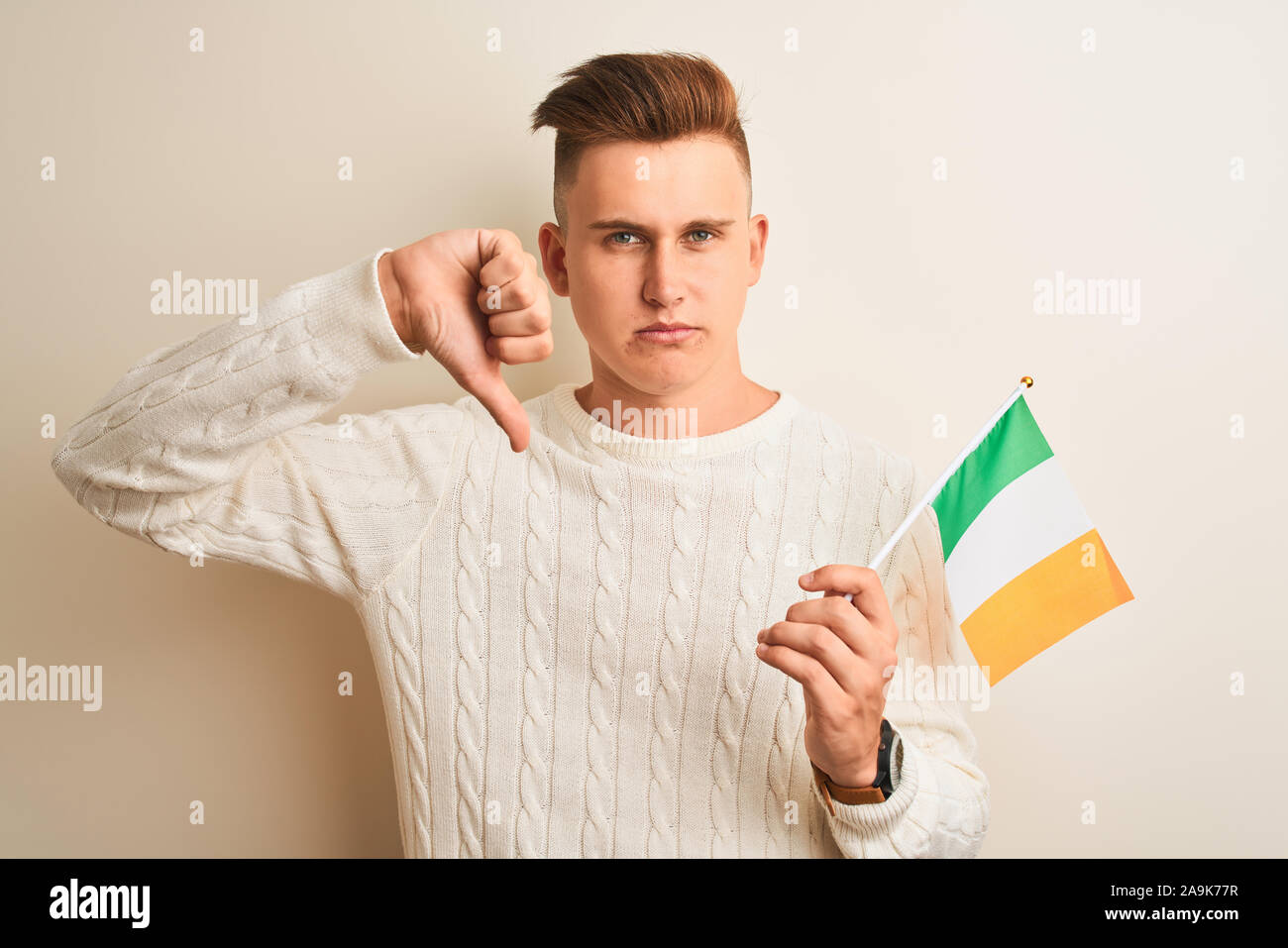 Young handsome man holding Ireland Irish flag over isolated white ...