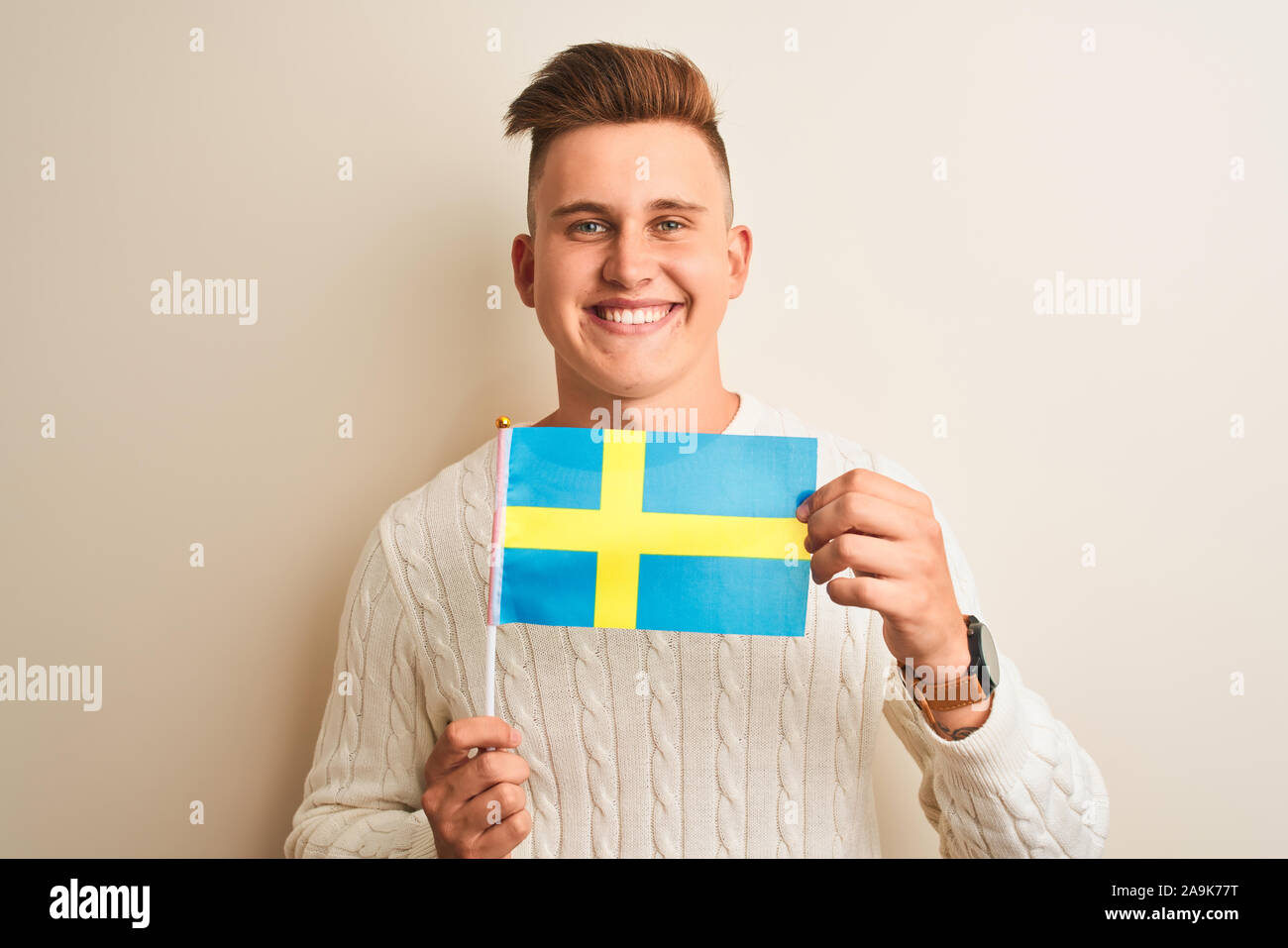 Young handsome man holding Sweadish Sweden flag over isolated white ...