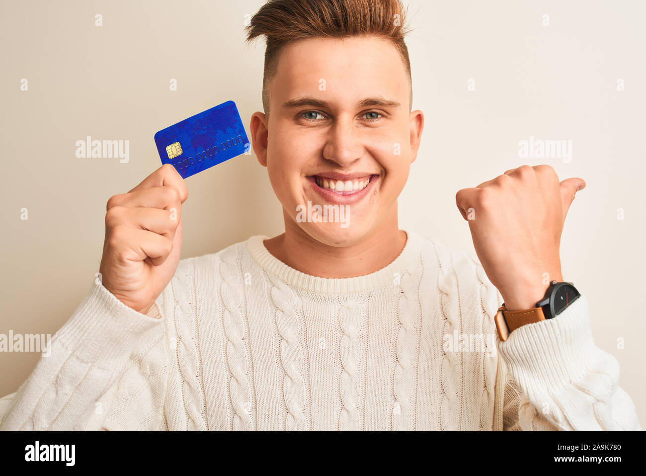 Young handsome man holding credit card over isolated white background ...