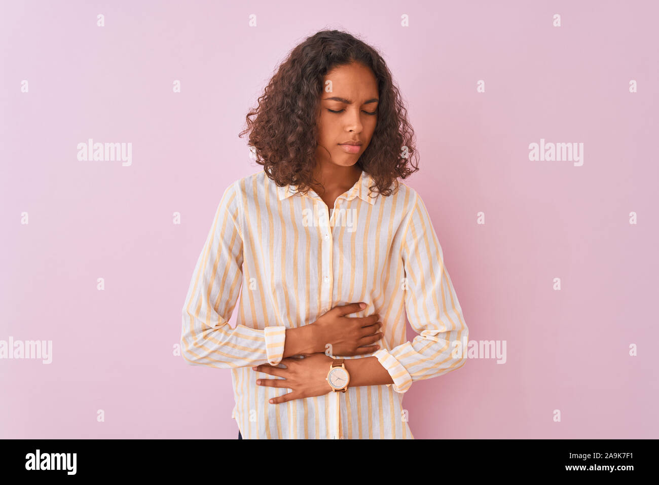 Young brazilian woman wearing striped shirt standing over isolated pink ...