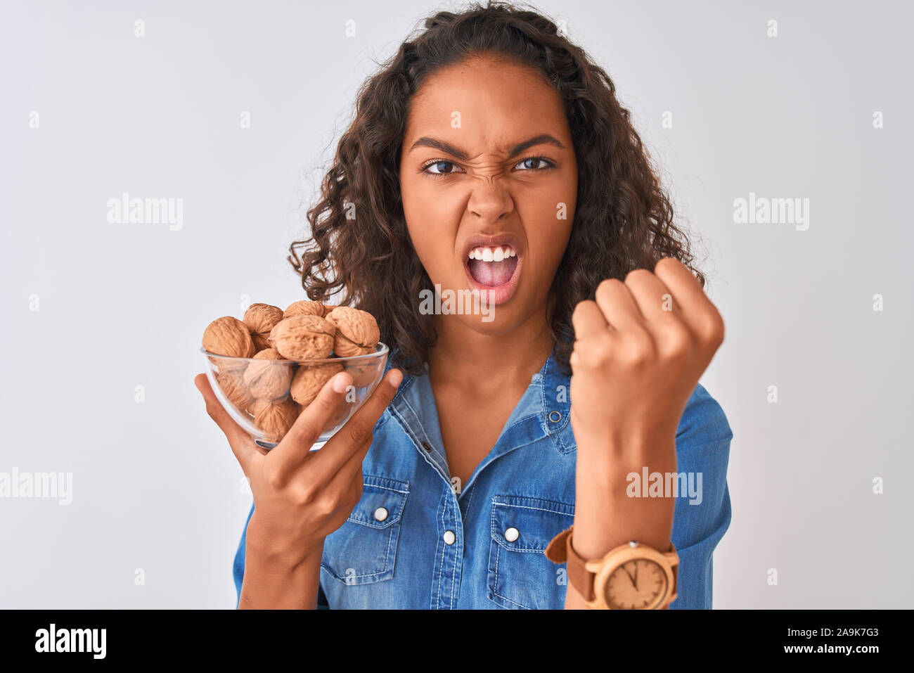 Young brazilian woman holding bowl with walnuts standing over isolated ...