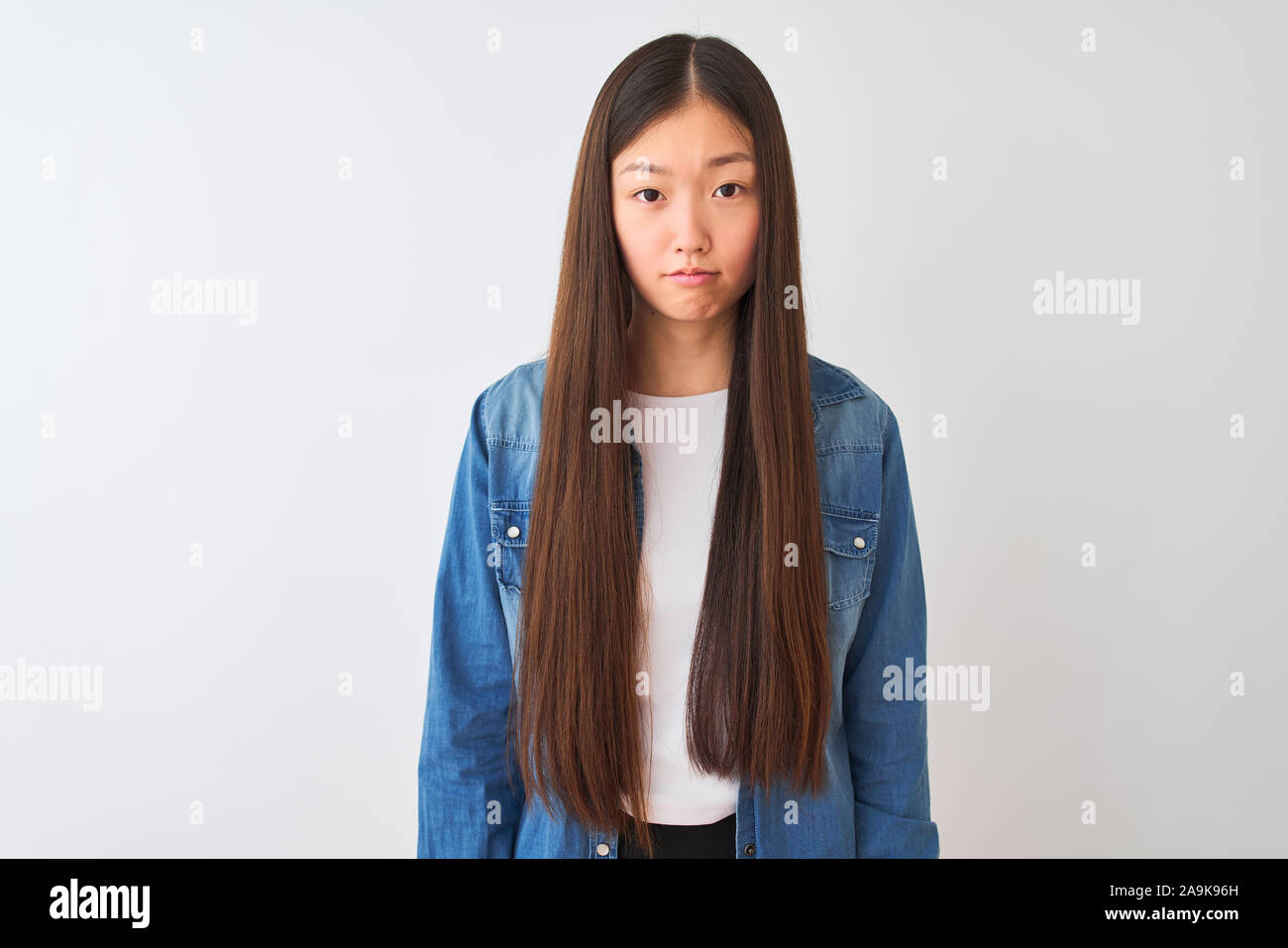 Young chinese woman wearing denim shirt standing over isolated white ...