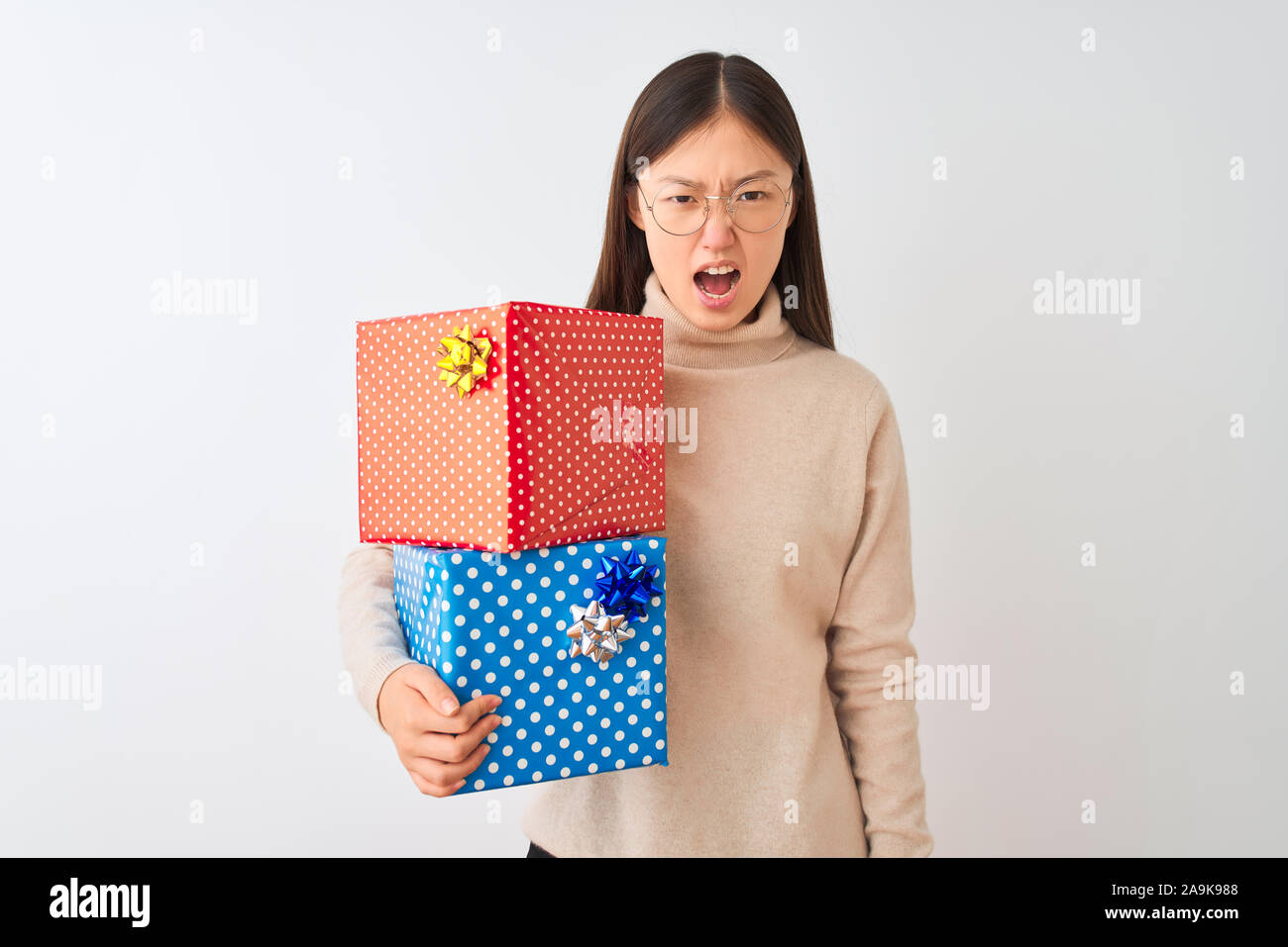 Young chinese woman holding birthday gifts over isolated white ...
