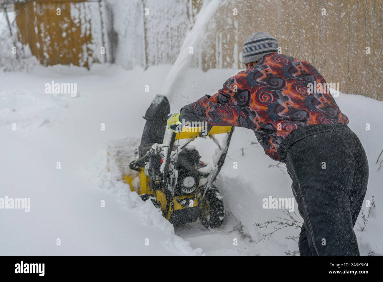 man operating snow blower to remove snow on driveway. Man using a ...