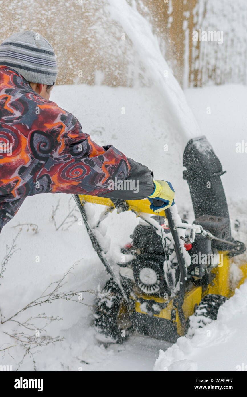 man operating snow blower to remove snow on driveway. Man using a ...