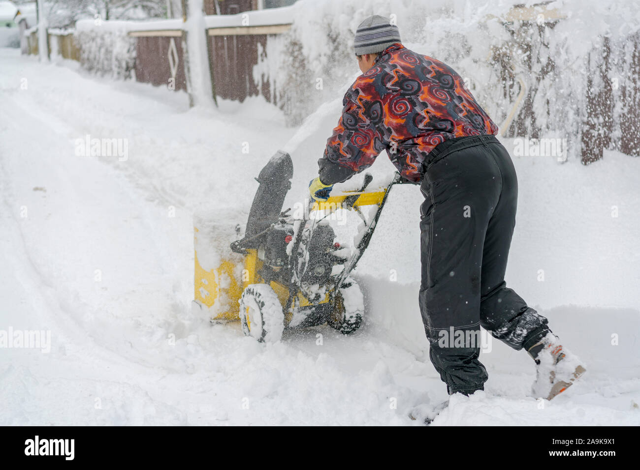 man operating snow blower to remove snow on driveway. Man using a ...
