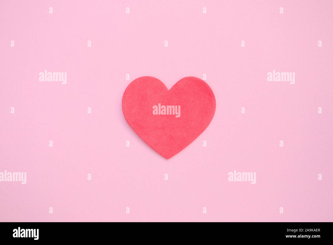 Looking down from above onto a single red heart shape on a pink ...