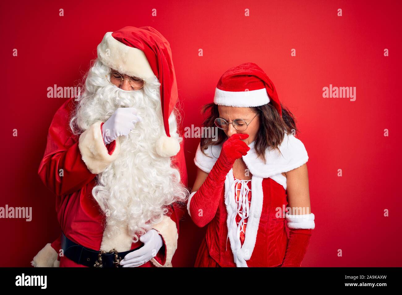 Middle age couple wearing Santa costume and glasses over isolated red ...