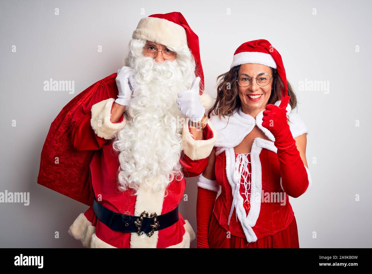 Senior couple wearing Santa Claus costume holding sack over isolated ...