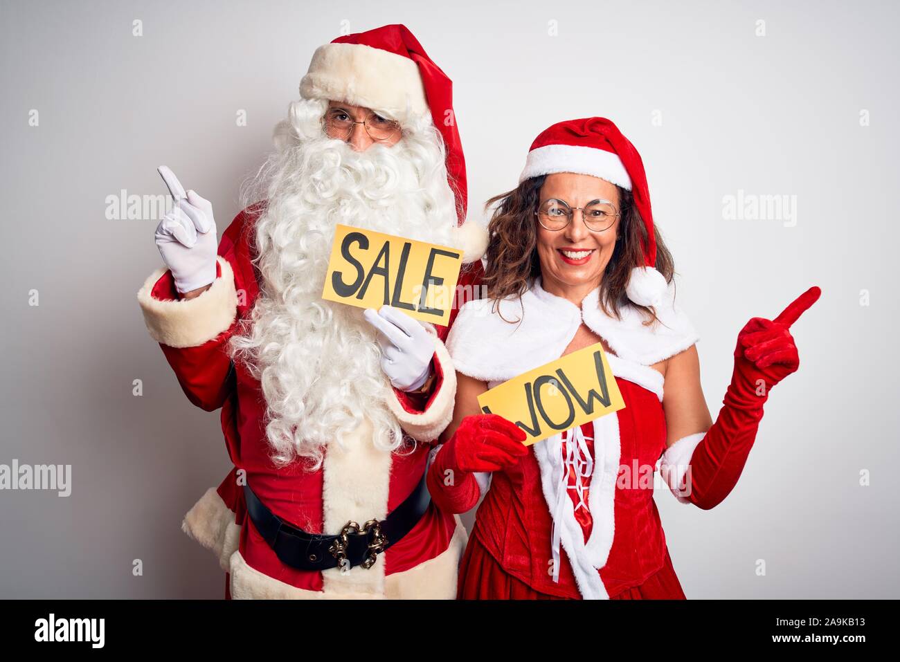 Couple wearing Santa costume holding wow and sale banner over isolated ...