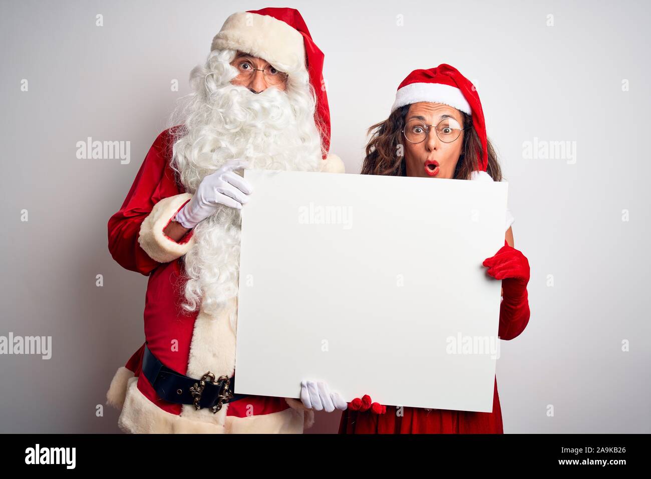 Senior couple wearing Santa Claus costume holding banner over isolated ...