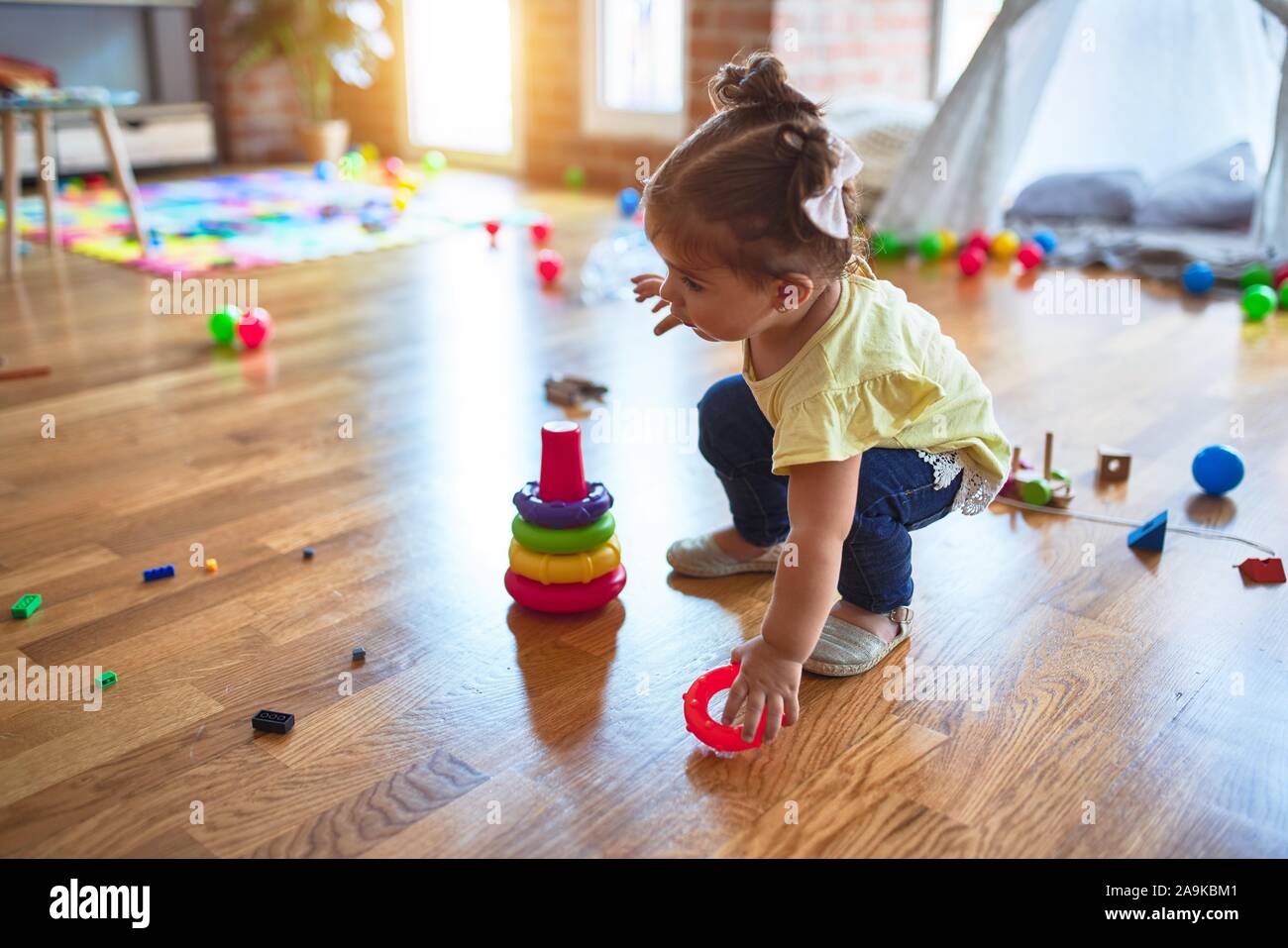 Beautiful toddler building pyramid with plastic hoops at kindergarten ...
