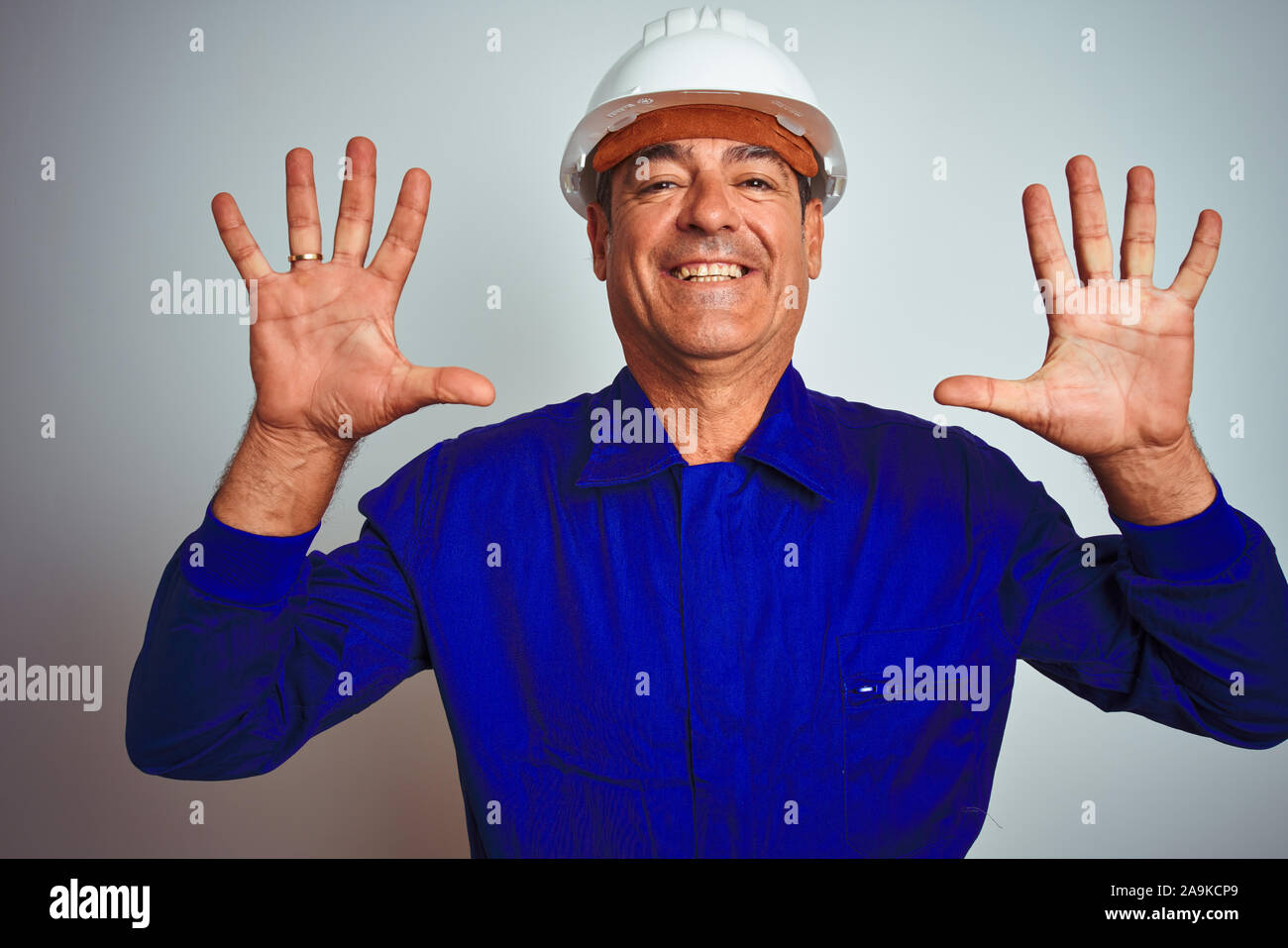 Handsome middle age worker man wearing uniform and helmet over isolated ...
