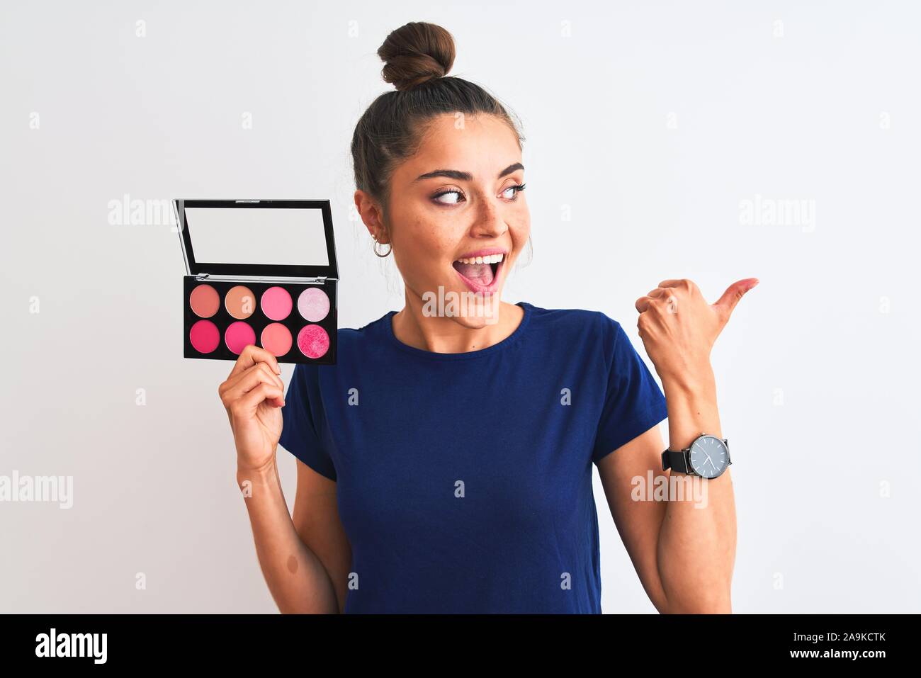 Young beautiful woman holding makeup standing over isolated white ...