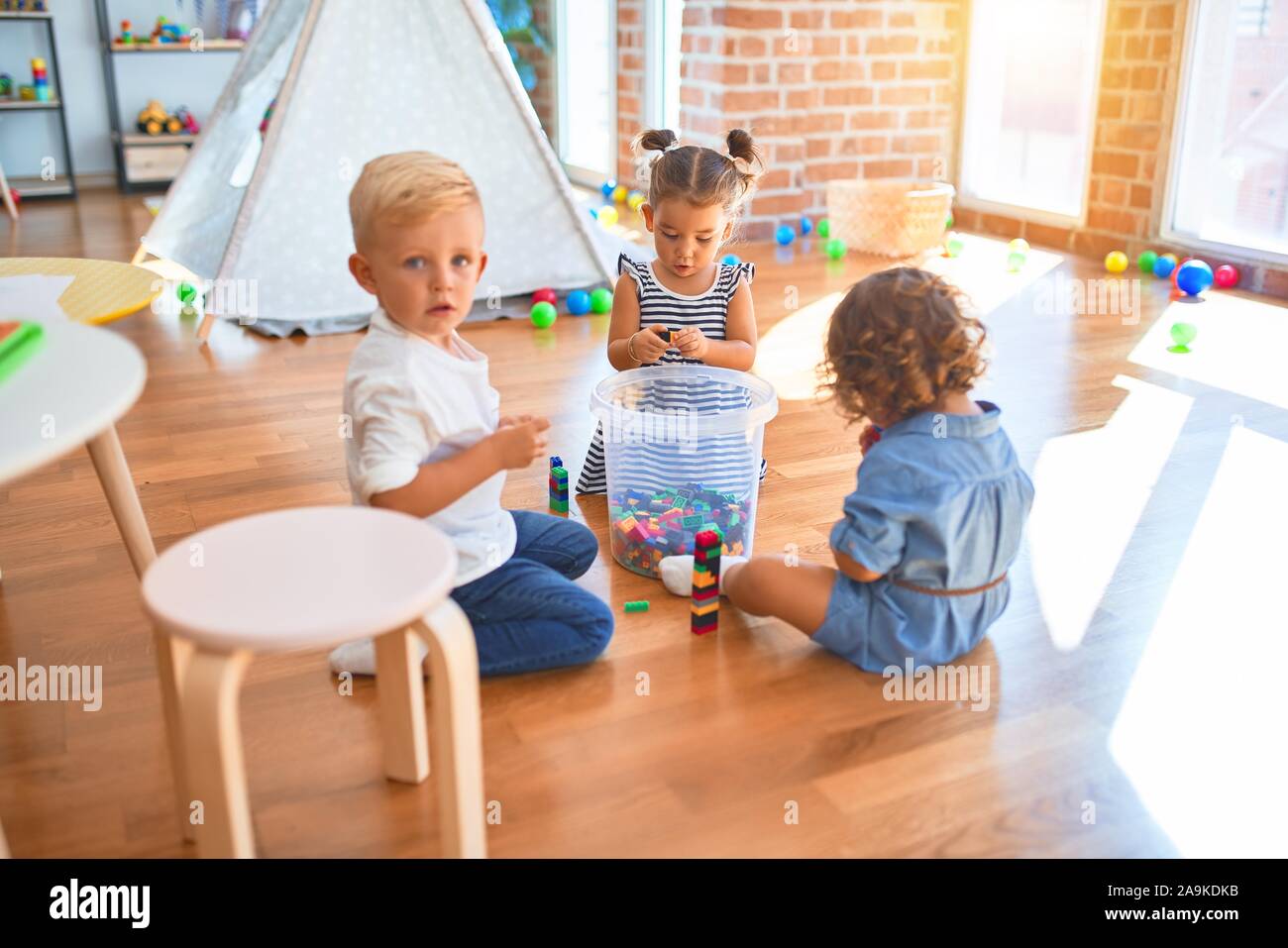 Adorable group of toddlers playing around lots of toys at kindergarten ...