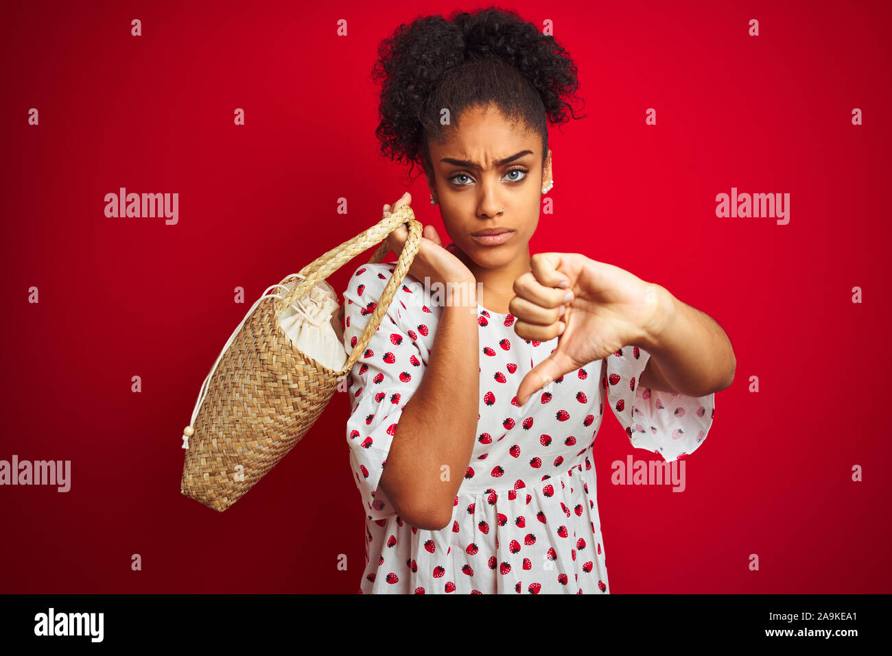 African american woman wearing fashion dress holding wicker bag over ...