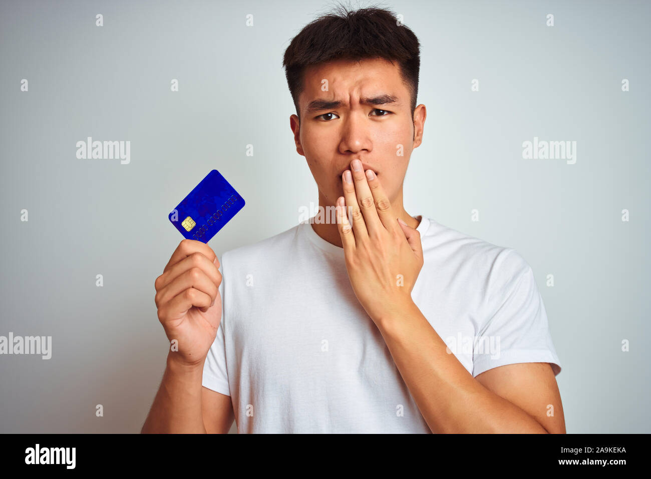 Young asian chinese man holding credit card standing over isolated ...