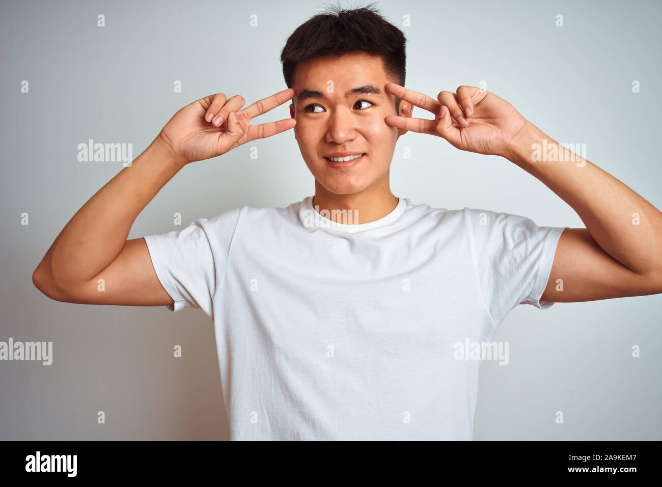 Young asian chinese man wearing t-shirt standing over isolated white ...