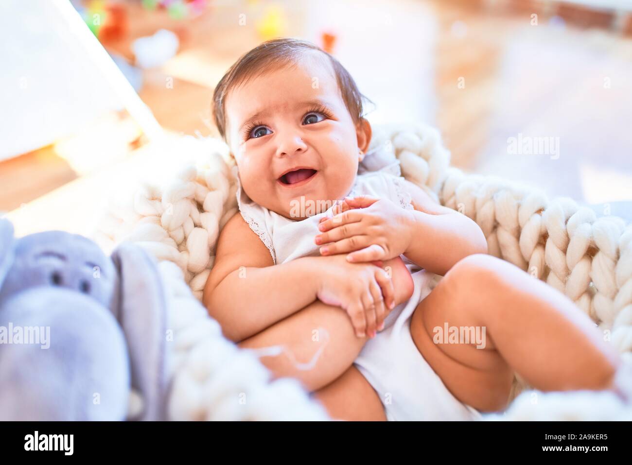 Beautiful infant happy at kindergarten around colorful toys lying ...