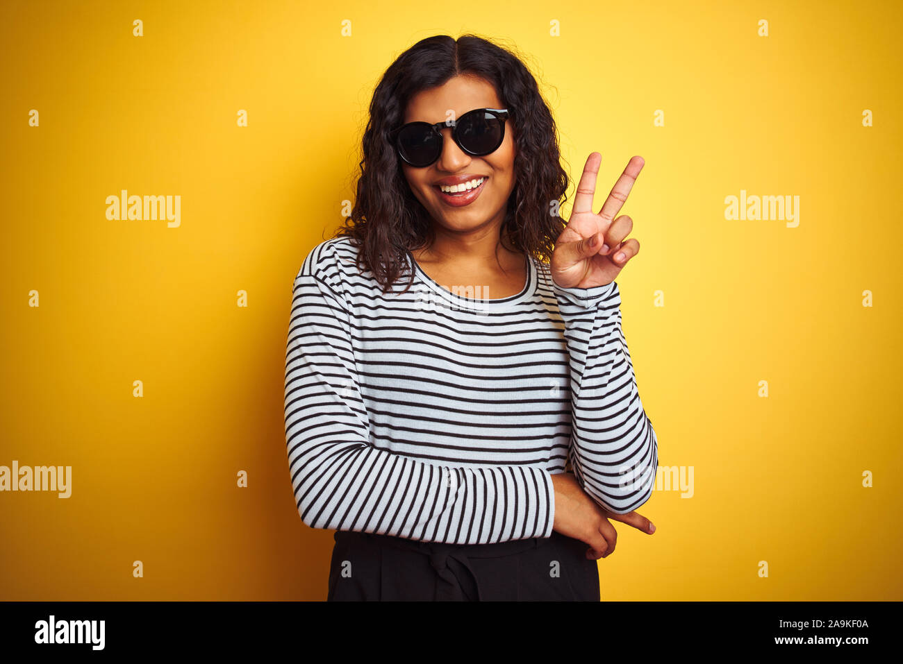 Transsexual transgender woman wearing sunglasses over isolated yellow ...