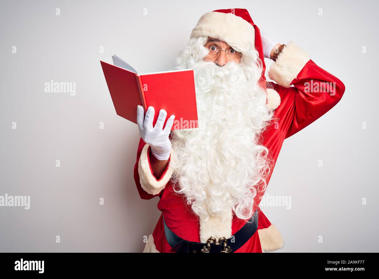 Middle age man wearing Santa Claus costume reading book over isolated ...