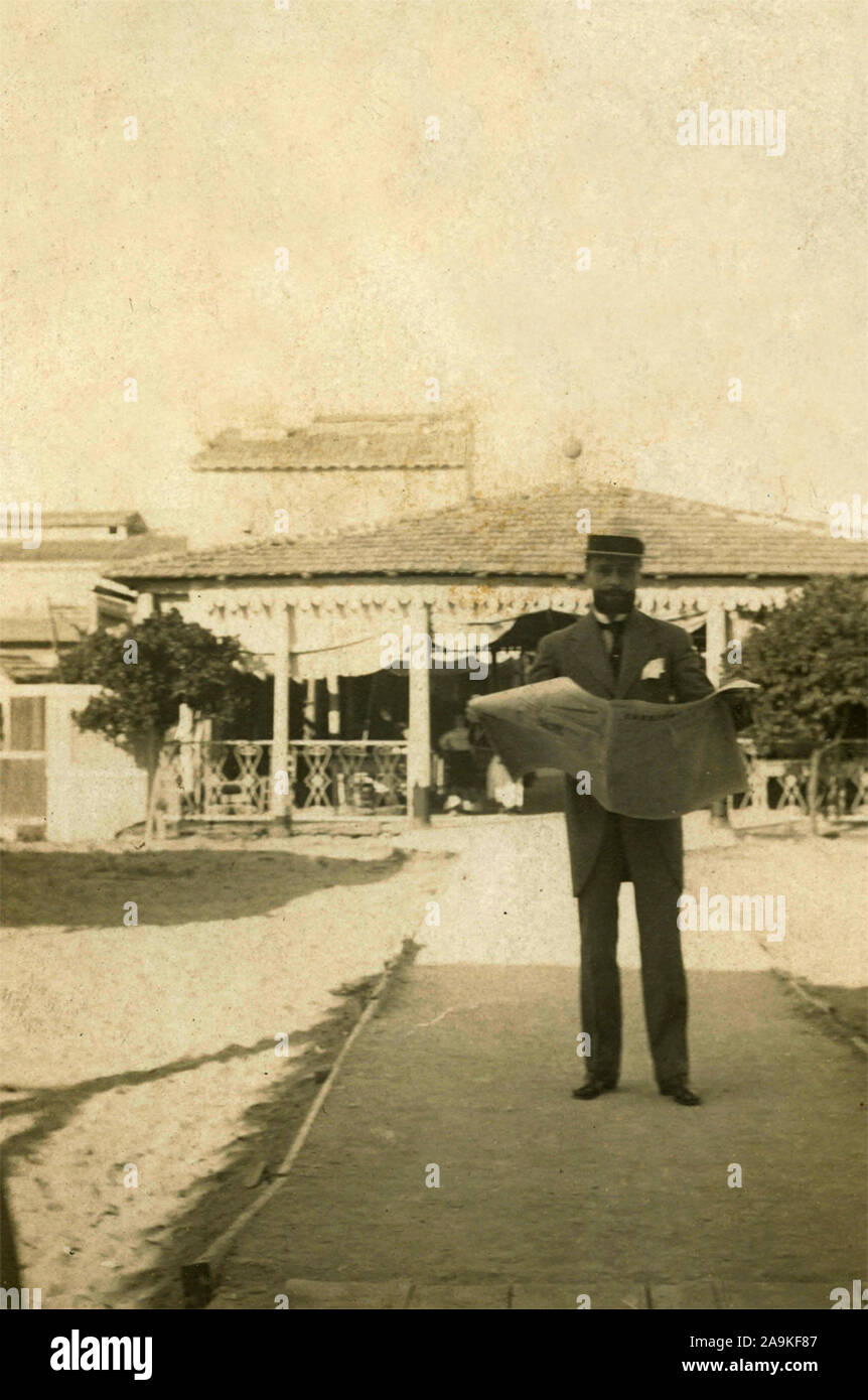 A straw-hatted man reading the newspaper stand, Italy Stock Photo - Alamy