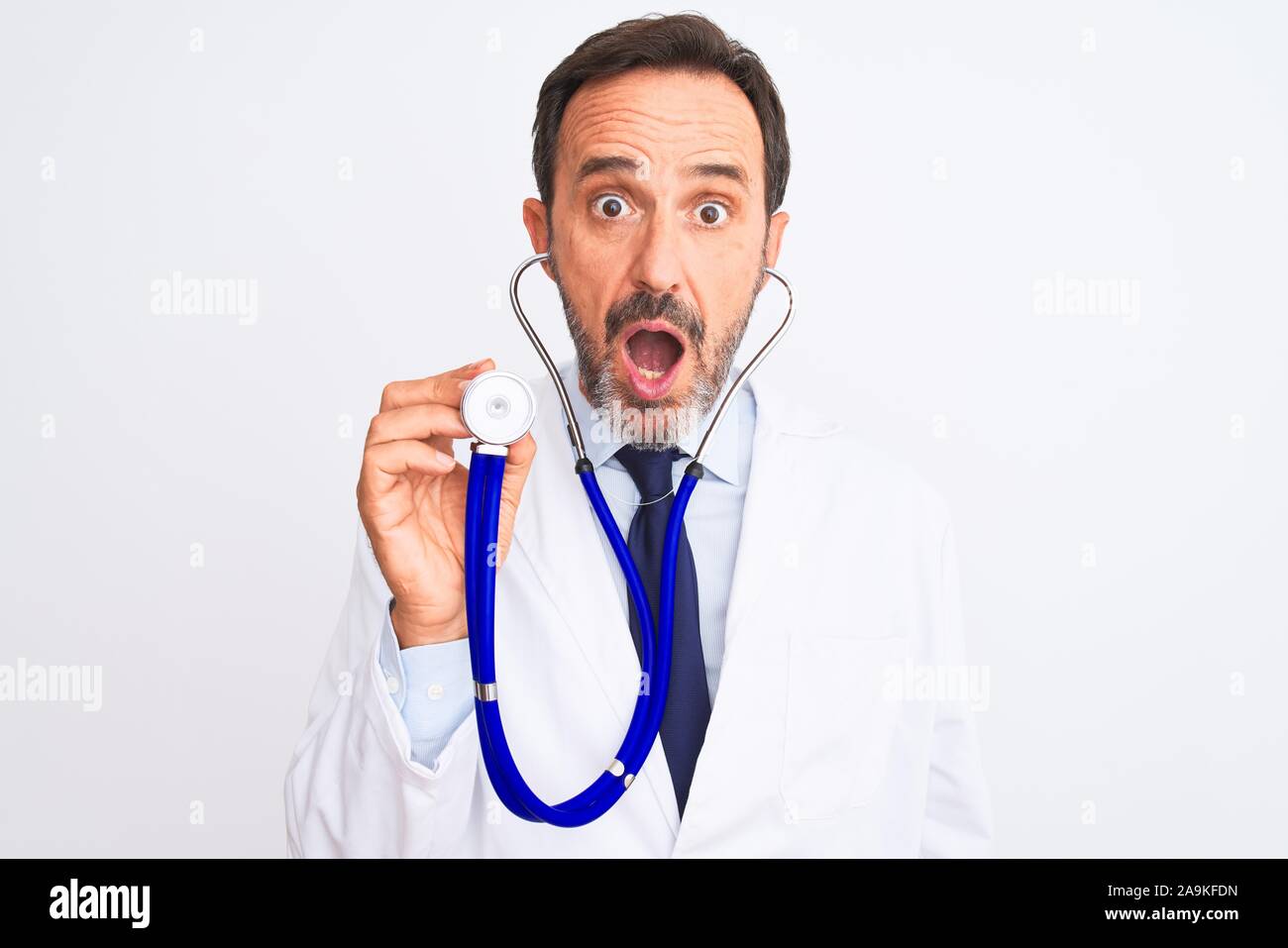 Middle age doctor man using stethoscope standing over isolated white ...