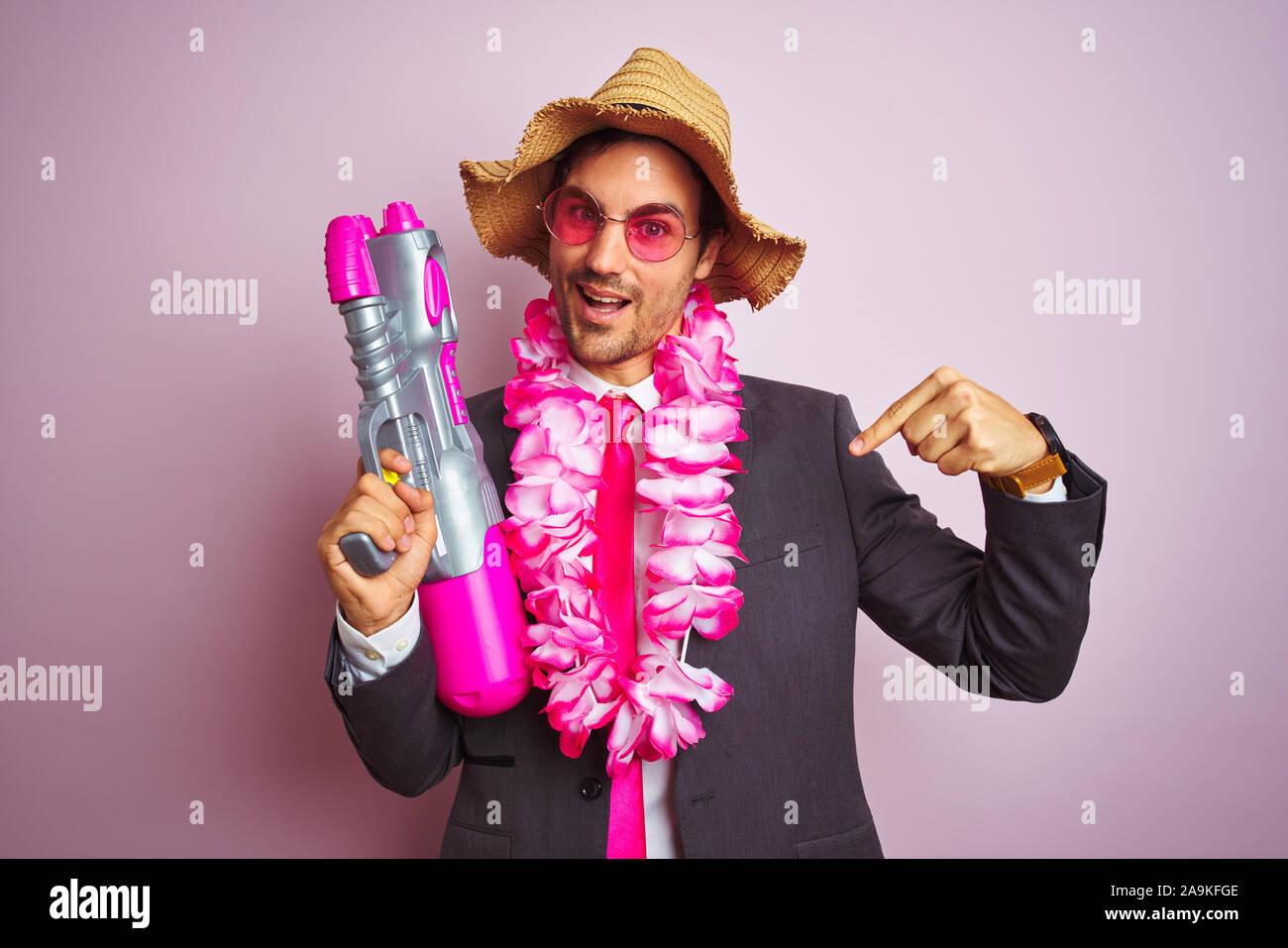 Young businessman wearing water gun hawaiian lei hat glasses over ...