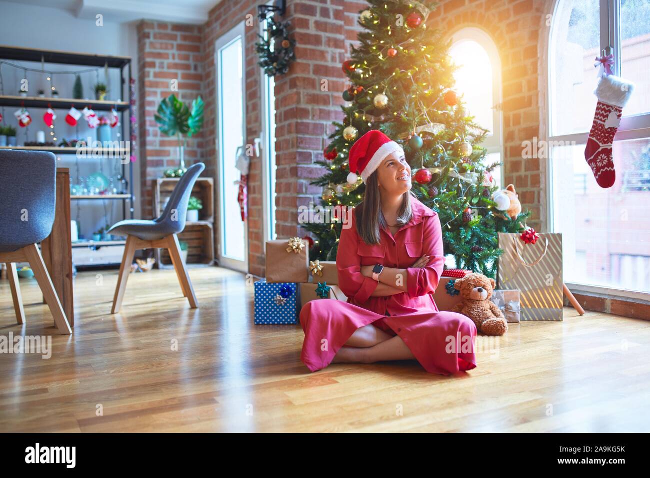 Beautiful woman sitting on the floor around christmas tree and presents ...