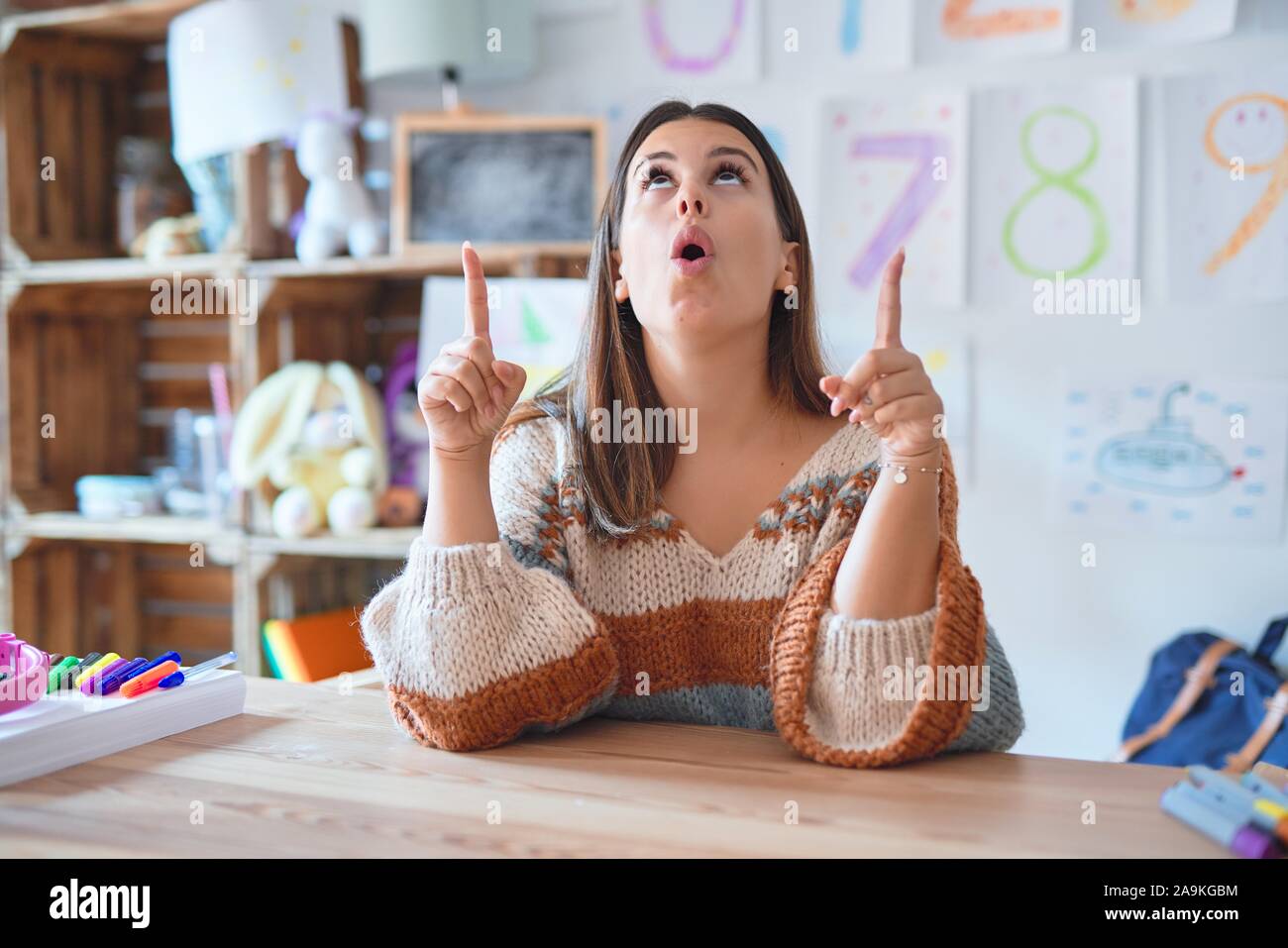 Young beautiful teacher woman wearing sweater and glasses sitting on ...