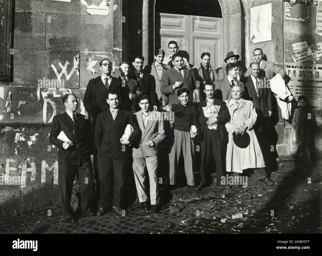 A large group next to walls and defaced posters, Italy Stock Photo - Alamy