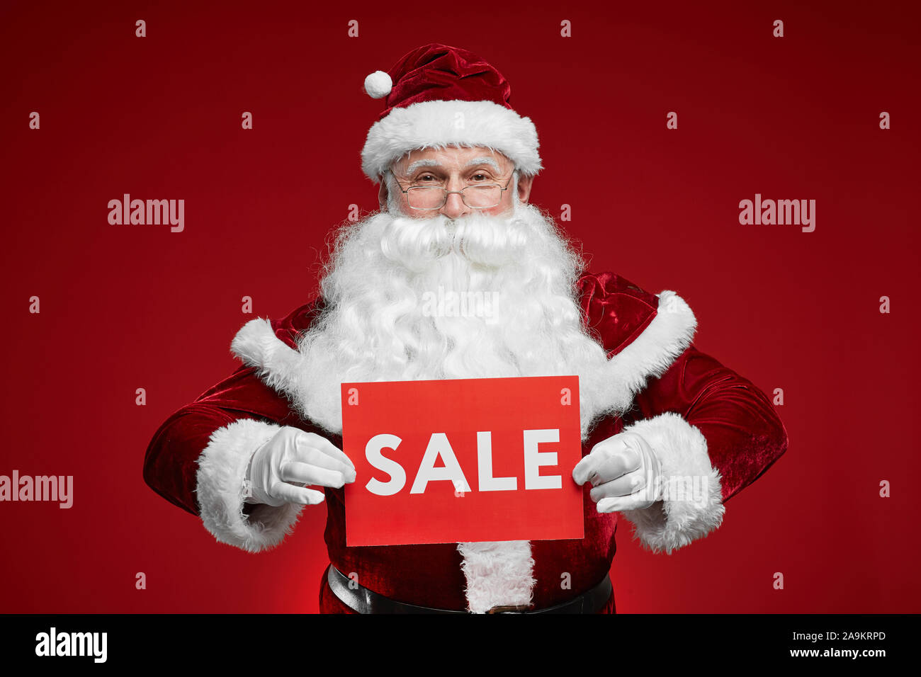 Portrait of St Nicholas holding sale sign and smiling at camera against ...