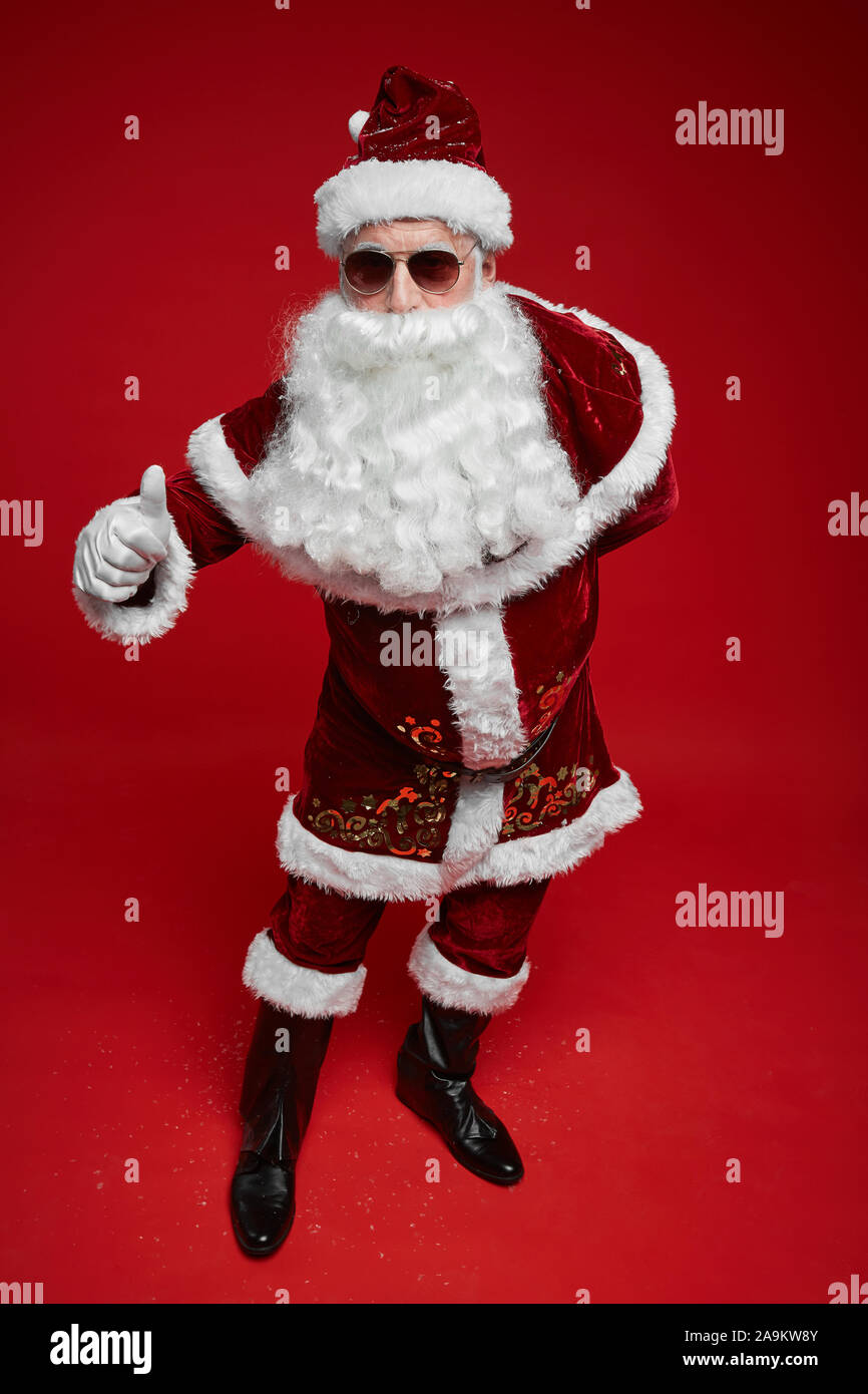 Portrait of fashion Santa Claus in sunglasses standing and showing ...