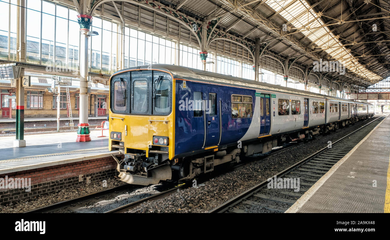 Blue and yellow commuter train at the platform of a Victorian-style ...