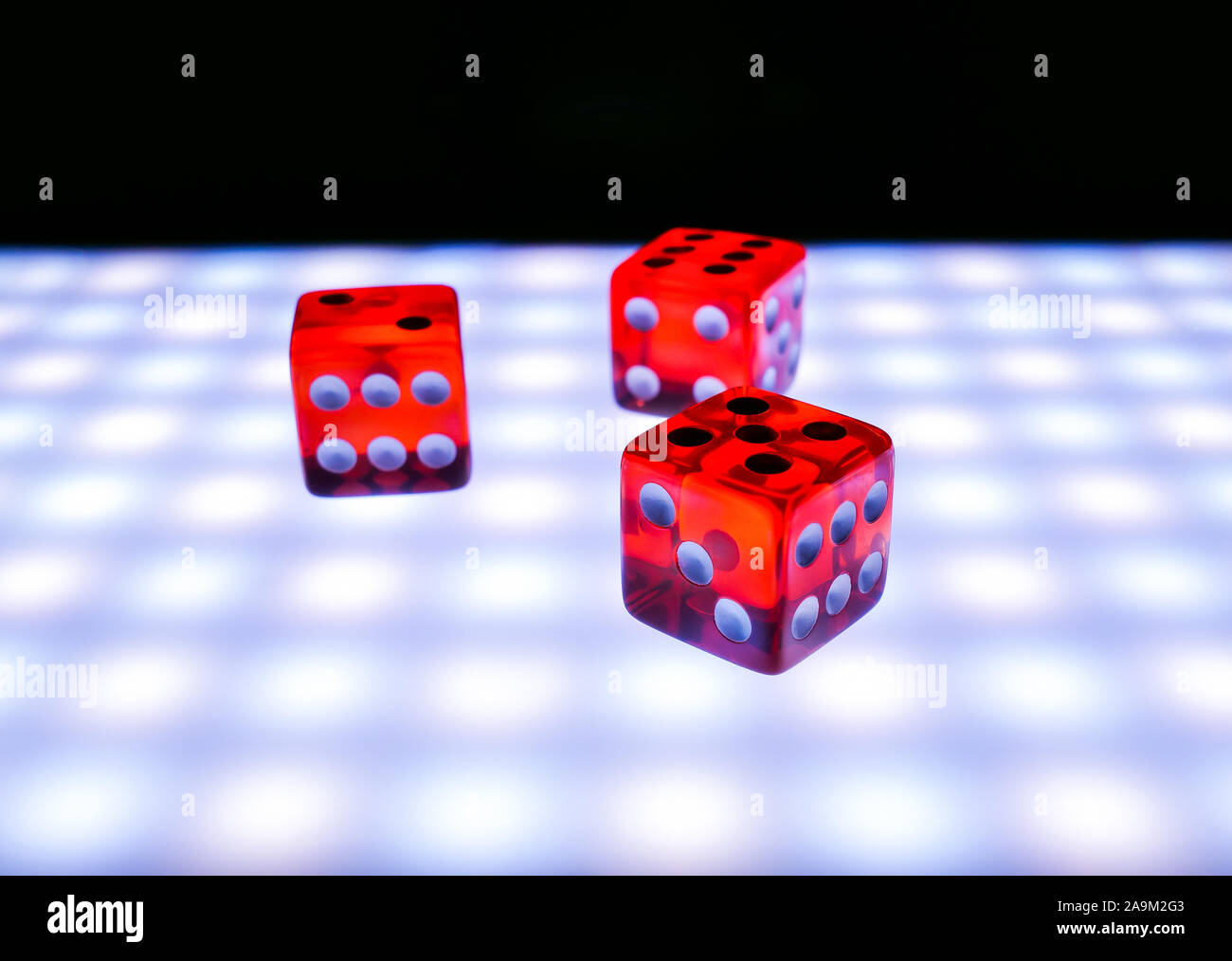 Red dice on a luminous surface on a black background, concept of board ...