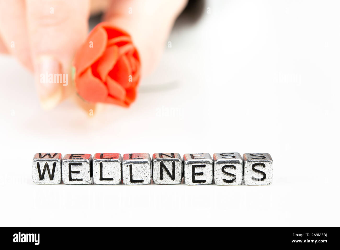 background wellness concept with cube letters and a woman hand holding ...