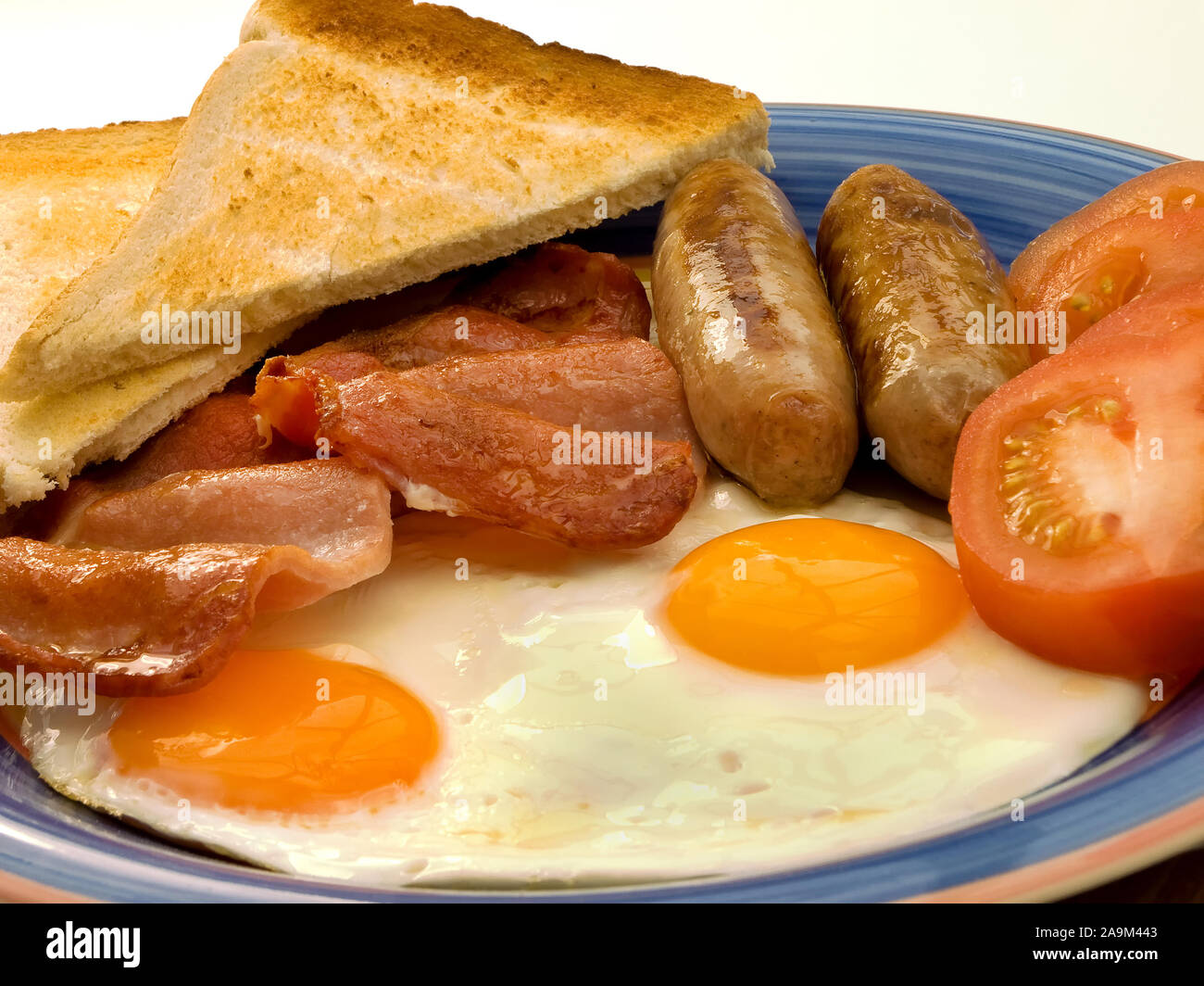 A traditional English breakfast plate with two eggs bacon tomatoes and ...