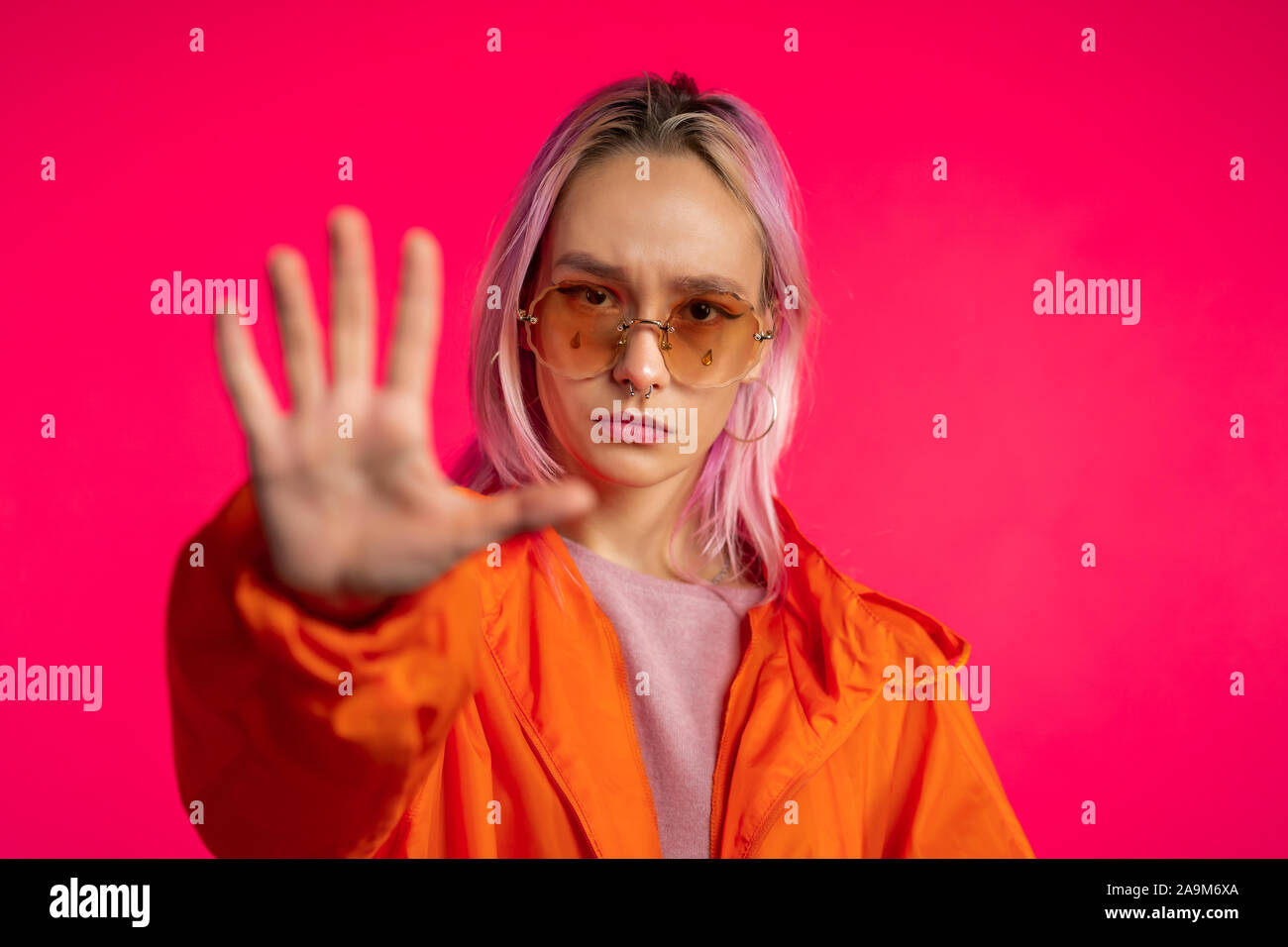 Annoyed girl with pink hair raising hand up to say no stop. Sceptical ...