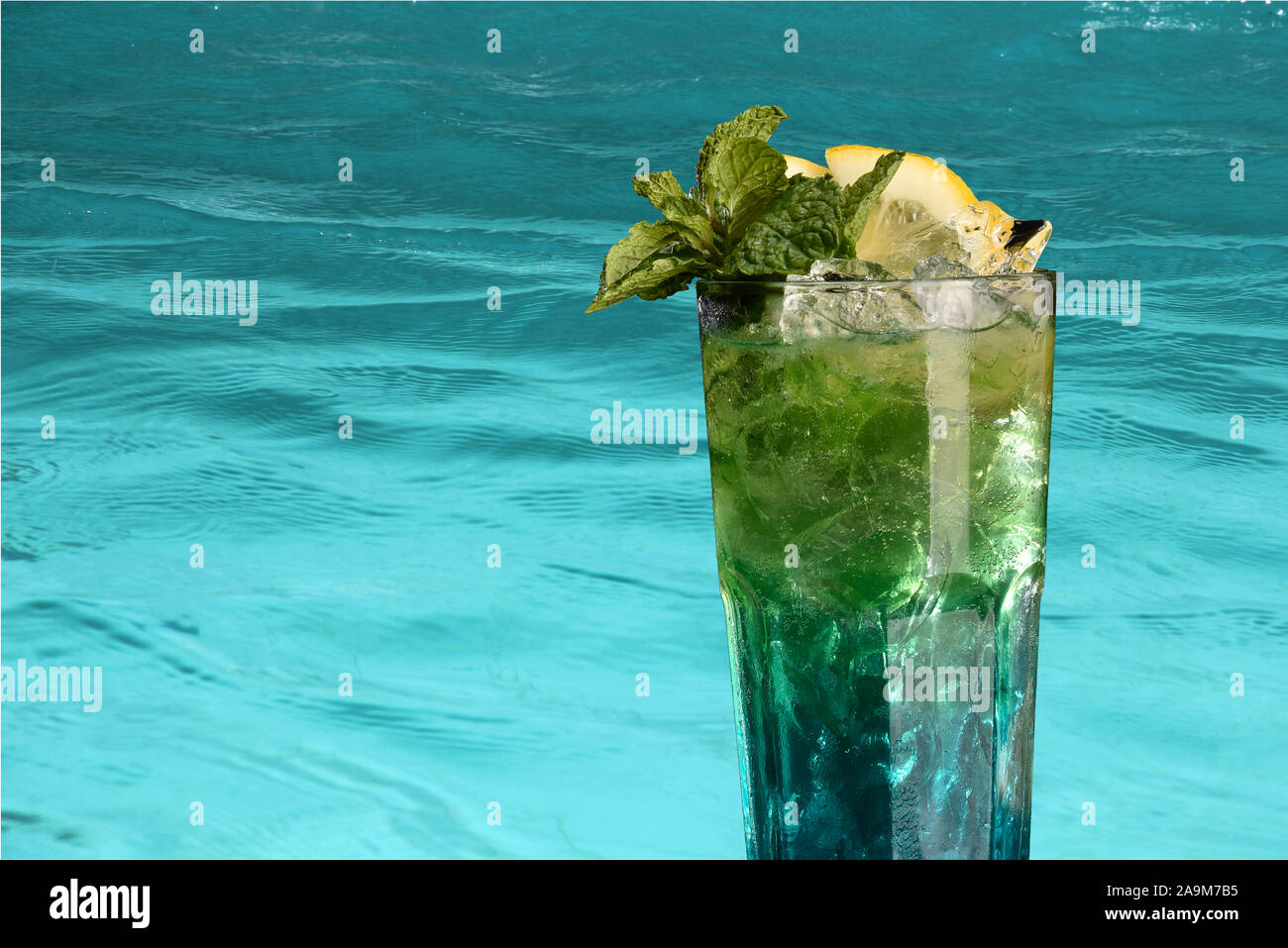 refreshing alcoholic drink in glass cup on the edge of the swimming ...