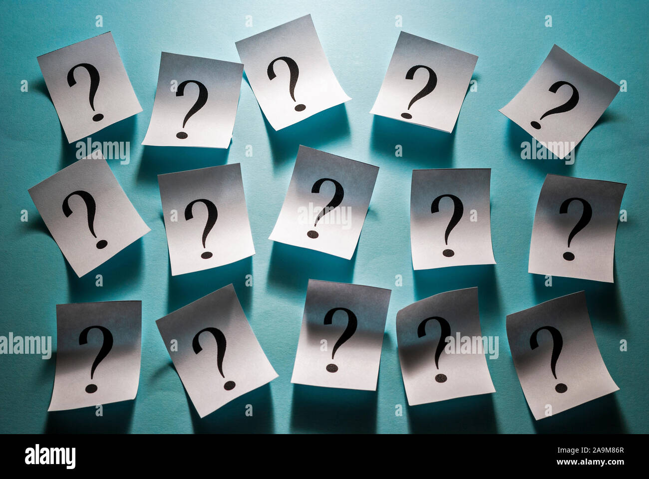 Printed question marks on white cards arranged in rows on a blue ...